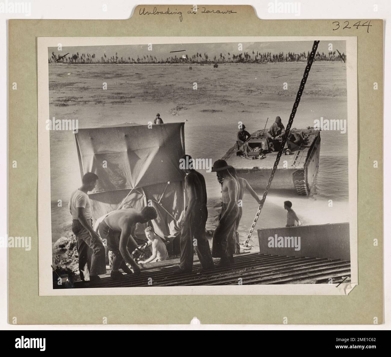 Coast Guardsmen aboard a Coast Guard-manned LST unload heavy equipment ...