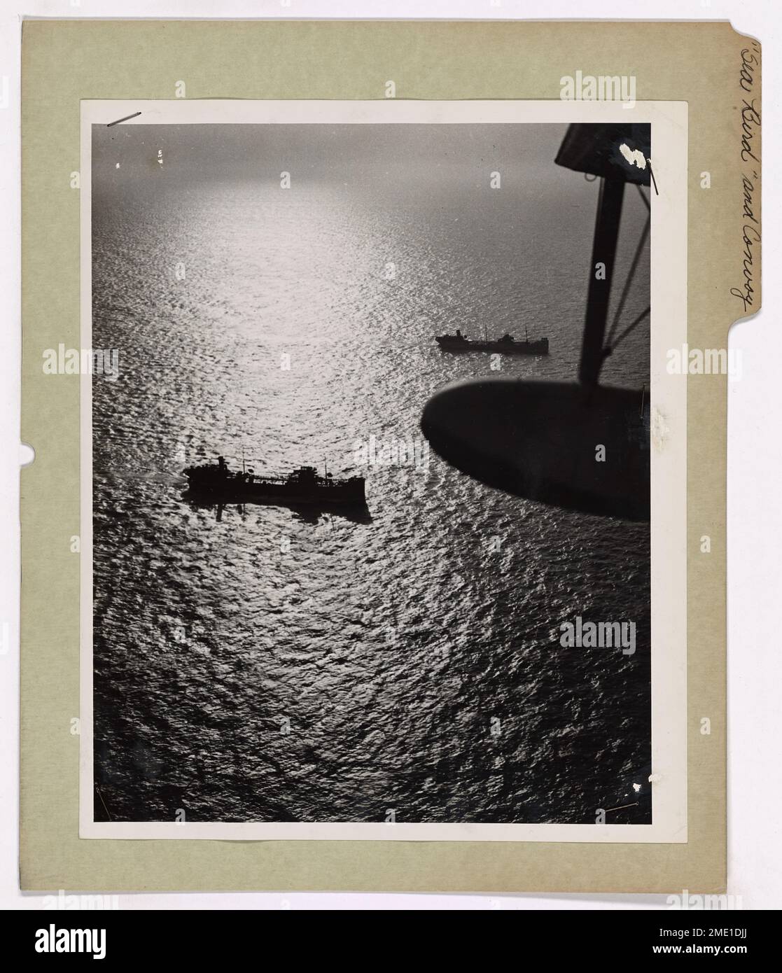 A Coast Guard 'Sea Bird' aircraft soars above a convoy of ships. The ...