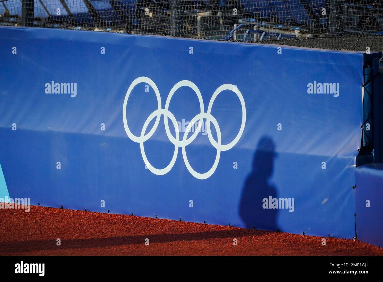 A shadow stands by the Olympic Rings ahead of a baseball game between ...