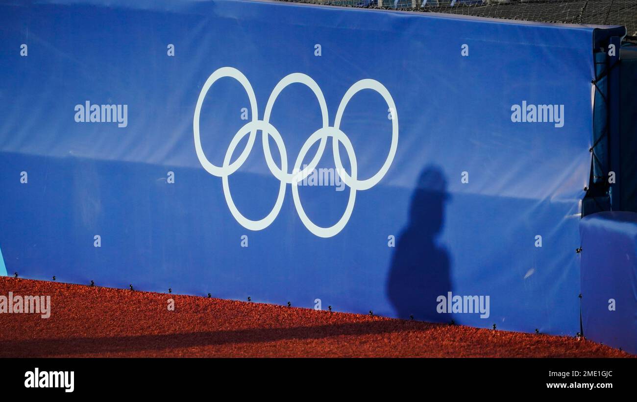 A shadow stands by the Olympic Rings ahead of a baseball game between ...