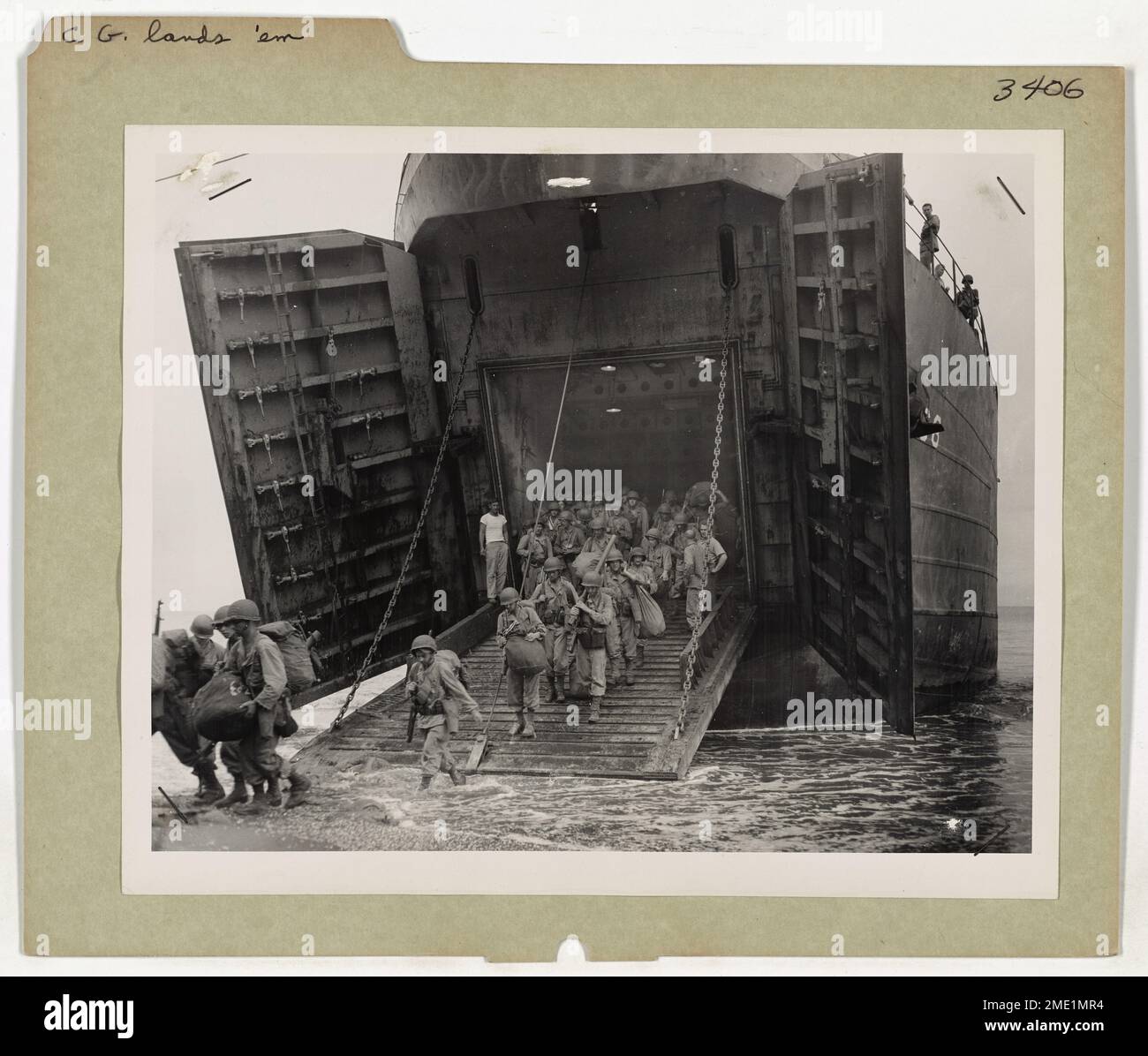 Coast Guardsmen aboard an LST open the bow doors as the ship lands on a ...