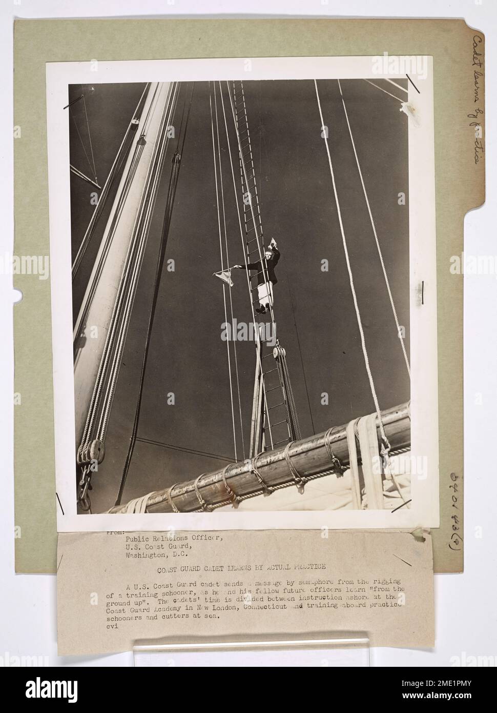 A U.S. Coast Guard cadet practices semaphore signaling from the rigging ...