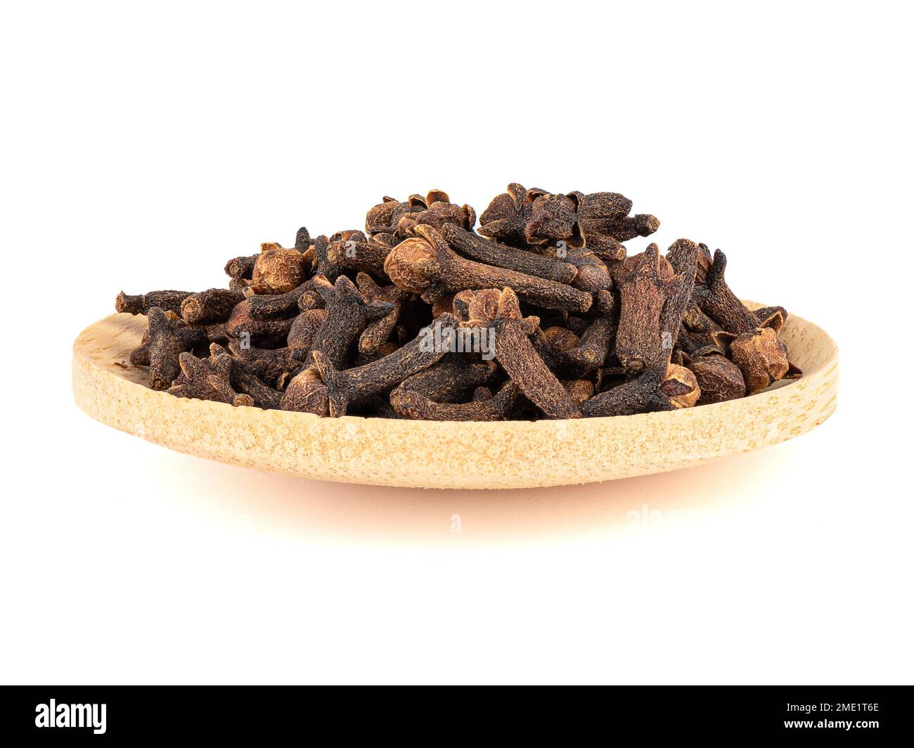 Cloves on a wooden plate isolated on a white background. A spice that ...