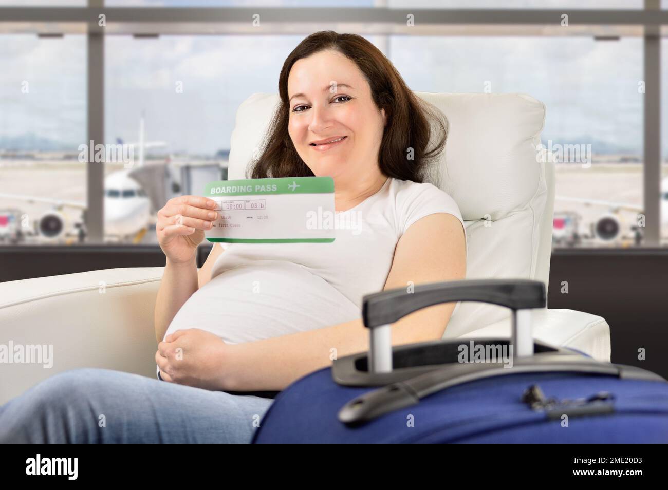 Pregnant woman holding boarding pass waiting for her flight in a VIP ...
