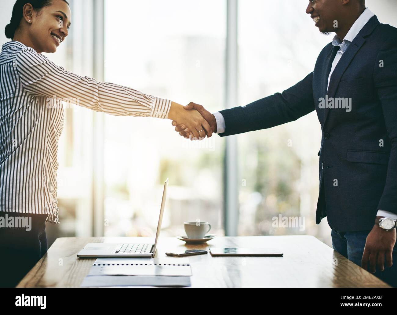 Working together will greatly benefit our company. two businesspeople shaking hands in an office ...