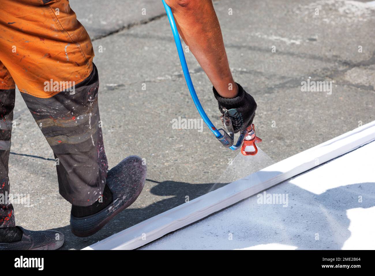 A road worker paints the road markings of a pedestrian crossing on a ...