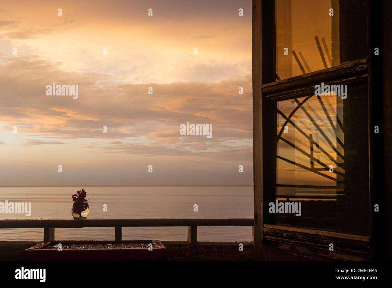 View from open window of calm ocean under cloudy colorful sundown sky ...