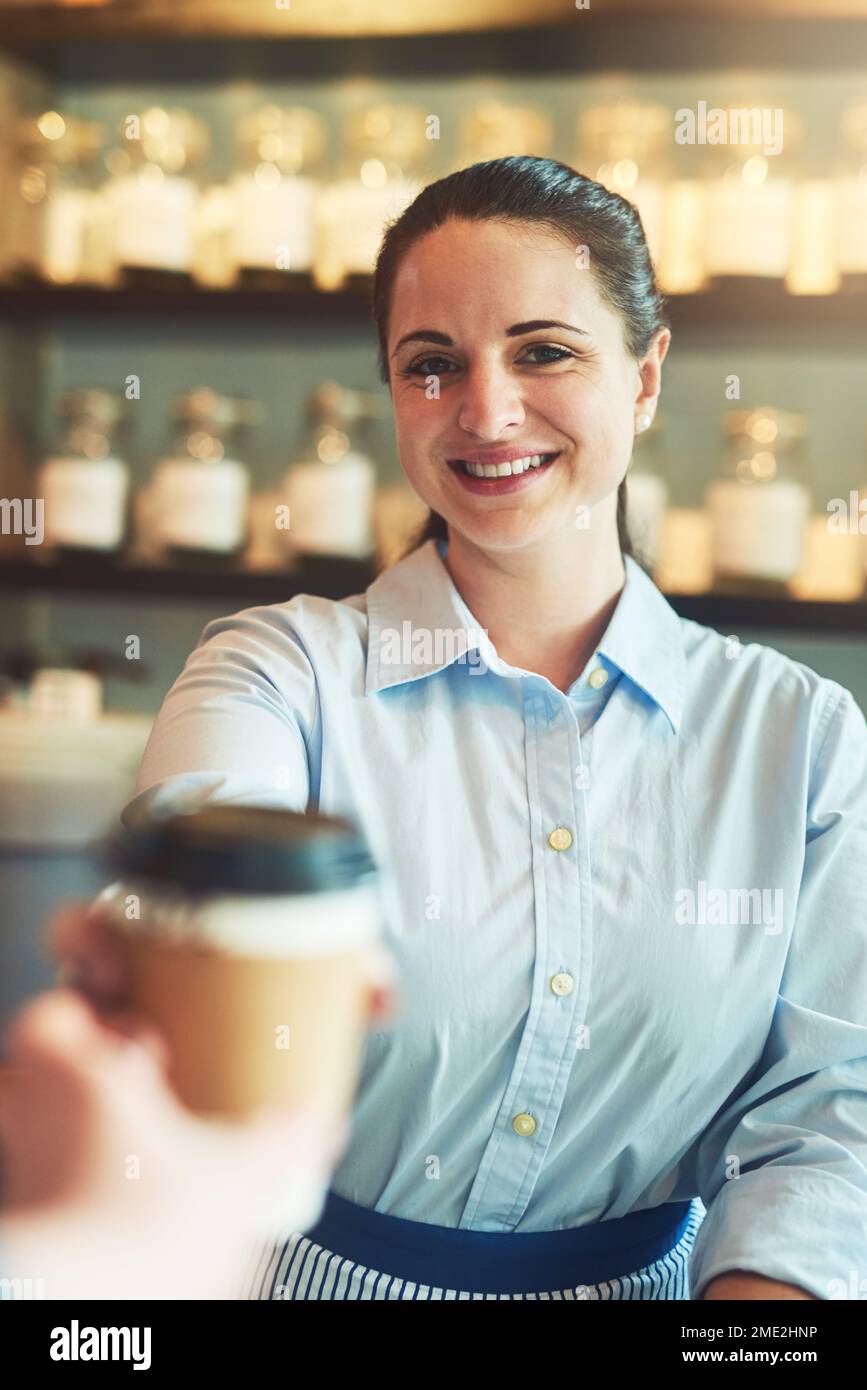 Service with a big smile. Portrait of a young barista giving a cup of ...