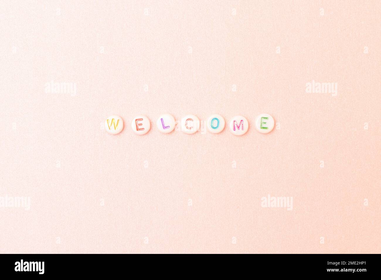 Word Welcome. Quote made of white round beads with multicolored letters ...