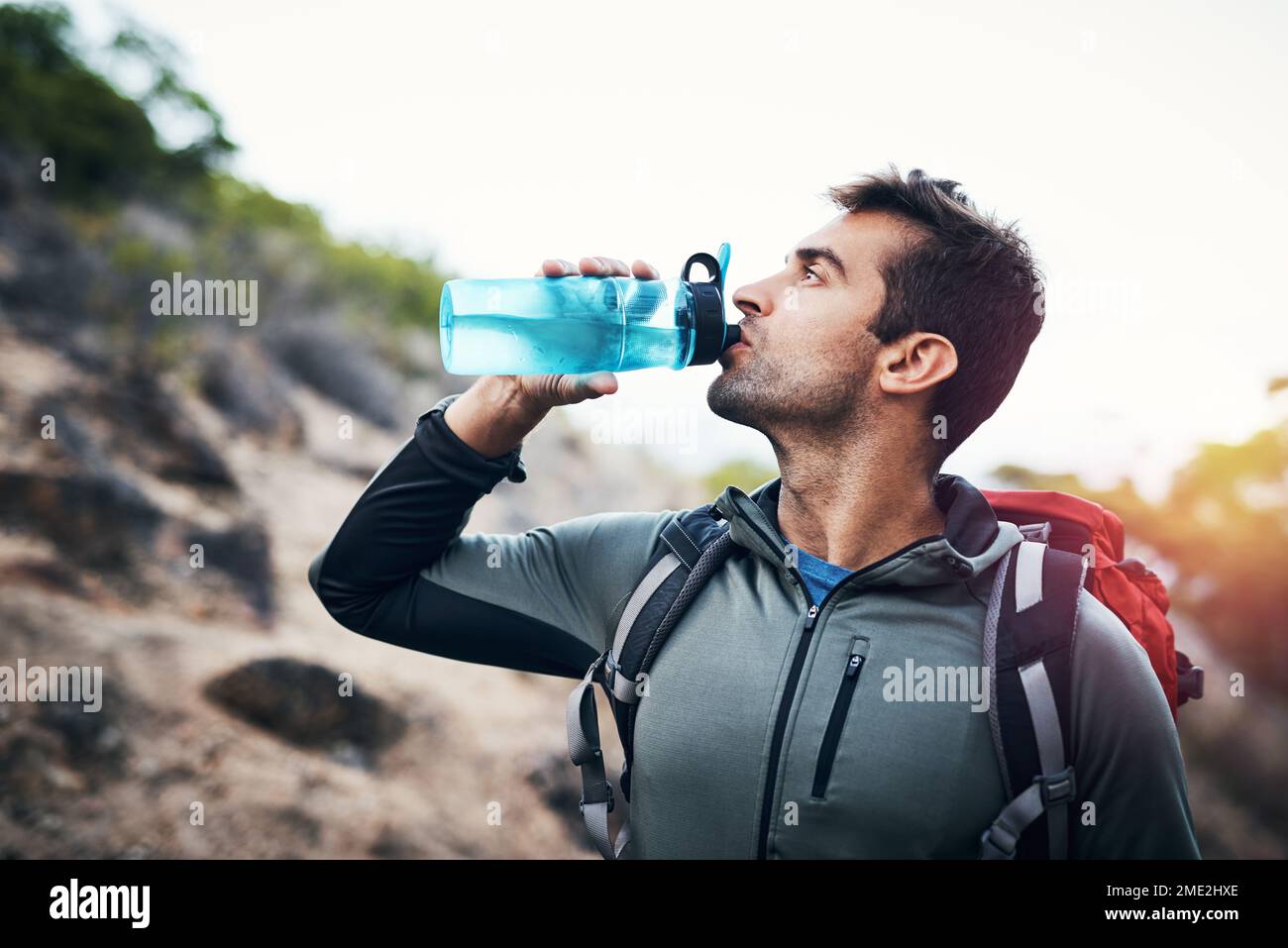 Its important to hydrate. a carefree young man drinking water from a ...