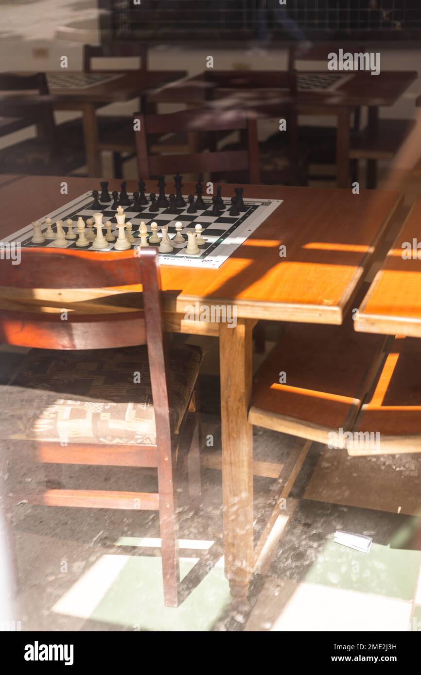 High angle view through window of wooden old tables with chess game in ...