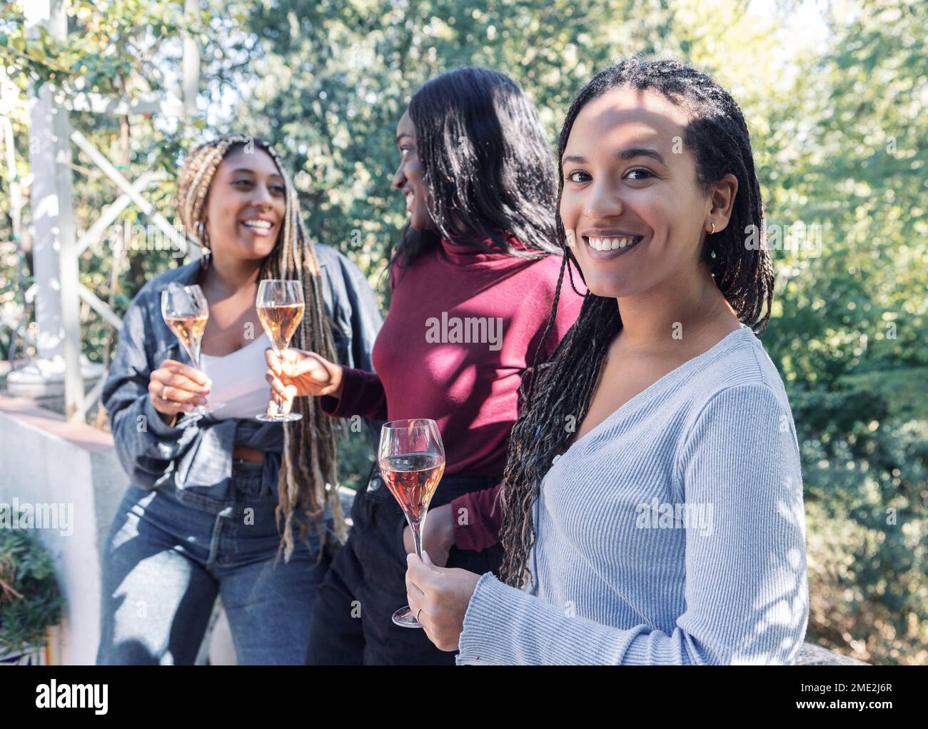 Happy multiracial female friends in casual clothes standing on terrace ...