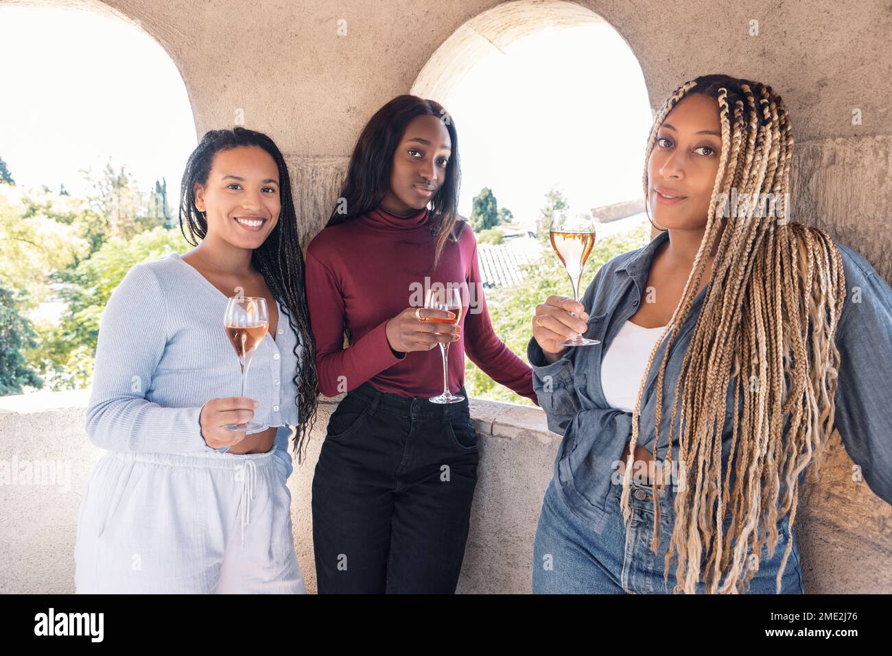 Multiracial female friends with glasses of champagne standing near ...