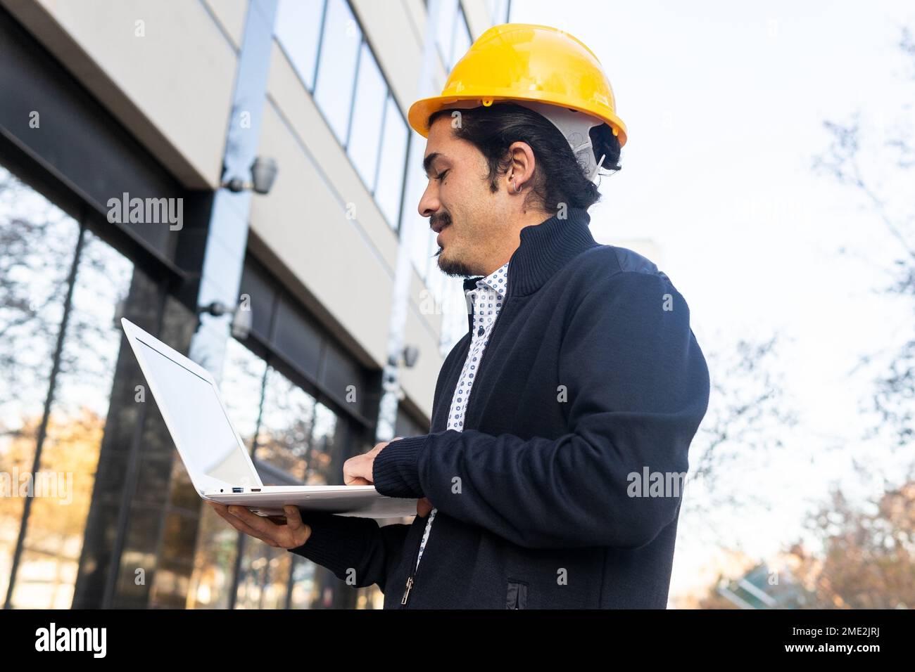 From below side view of positive young Hispanic male engineer in smart ...