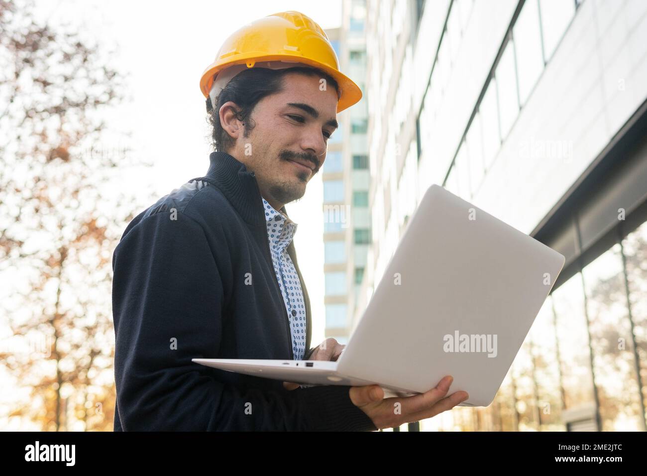 From below side view of positive young Hispanic male engineer in smart ...