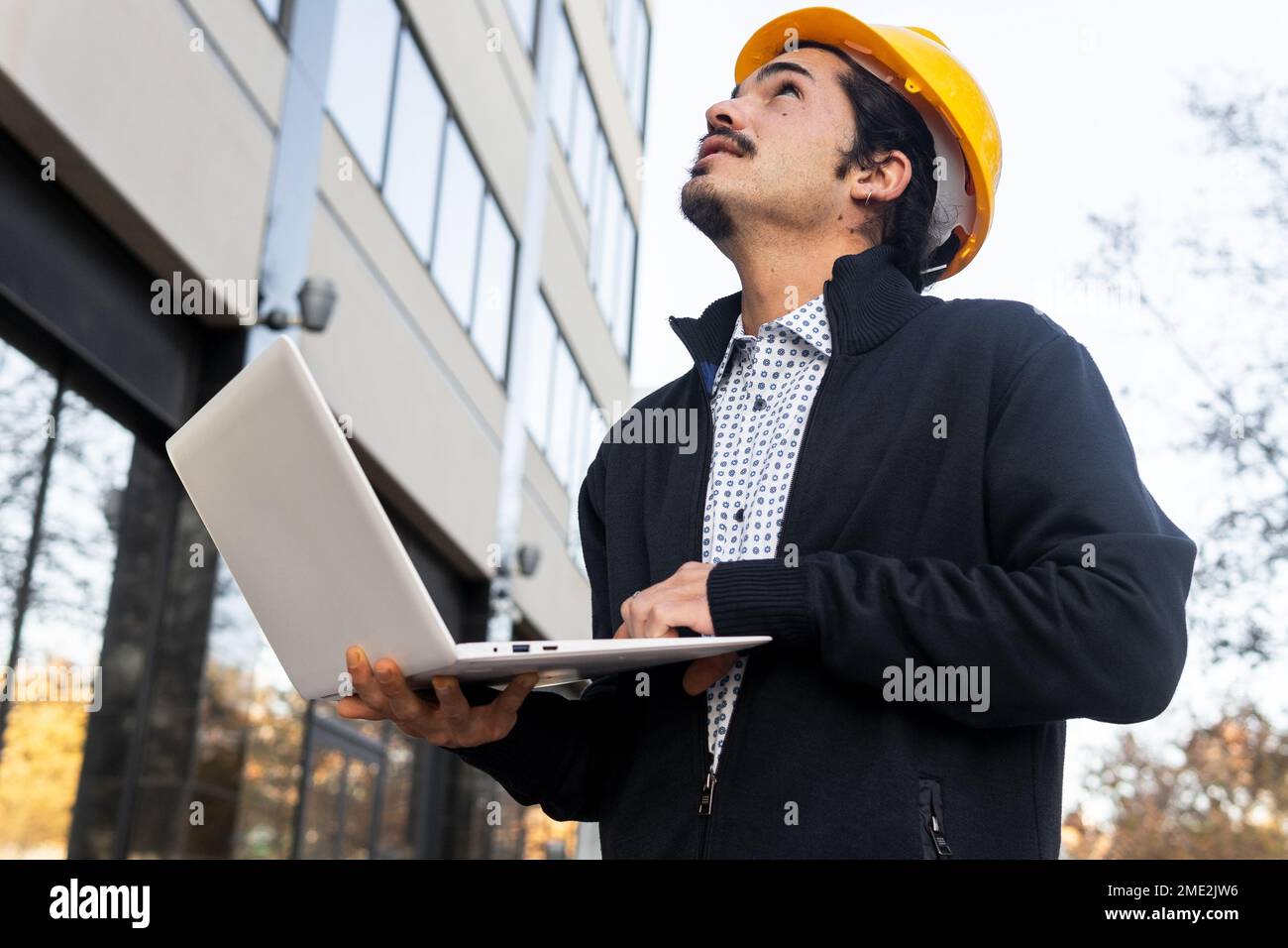 From below side view of positive young Hispanic male engineer in smart ...