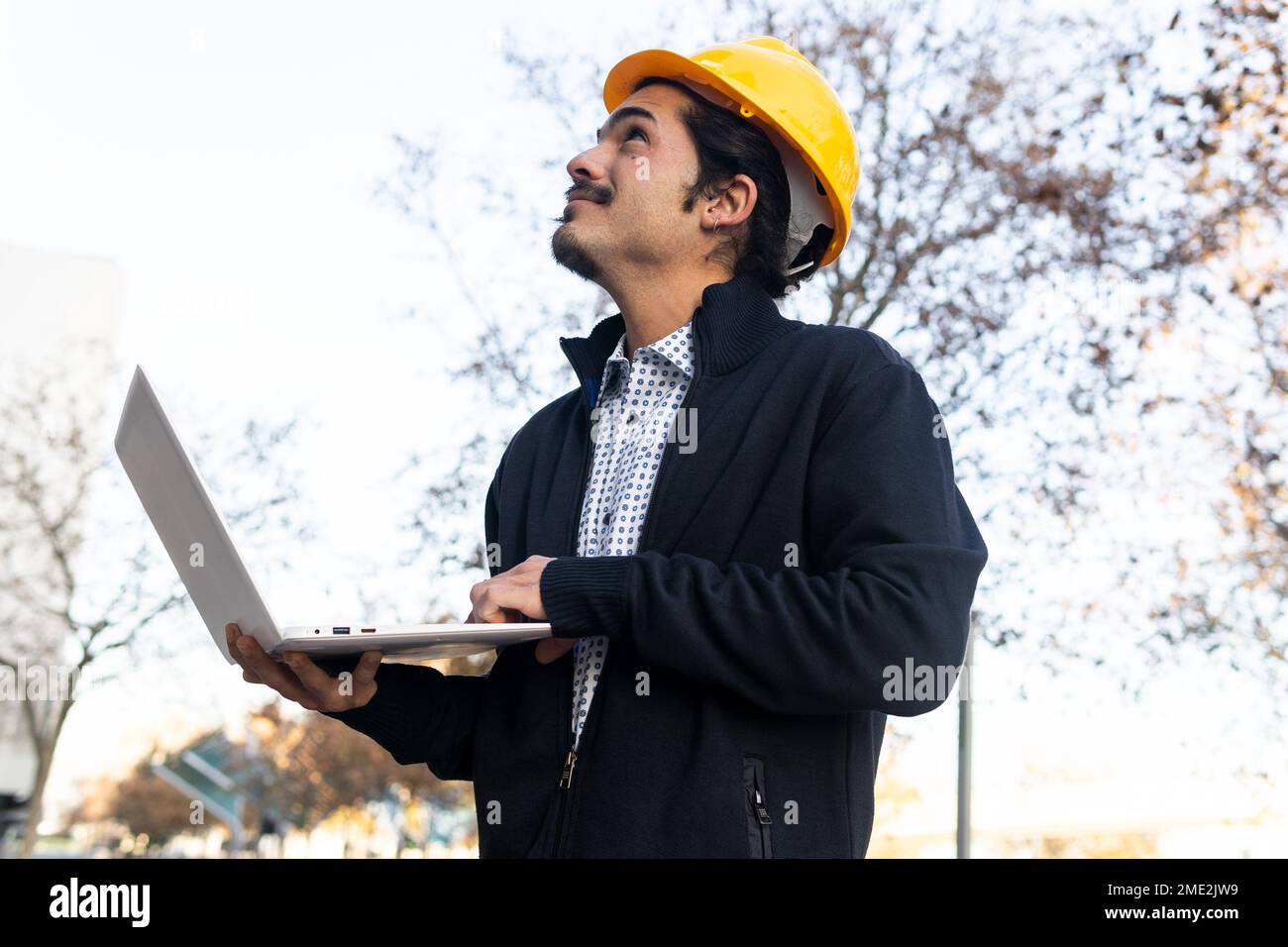 From below side view of positive young Hispanic male engineer in smart ...
