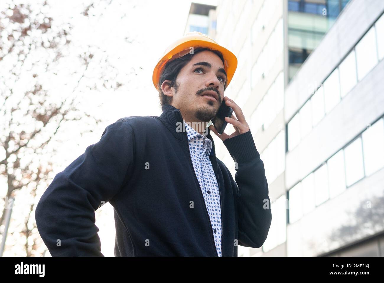 From below of concentrated young ethnic male contractor with dark hair ...