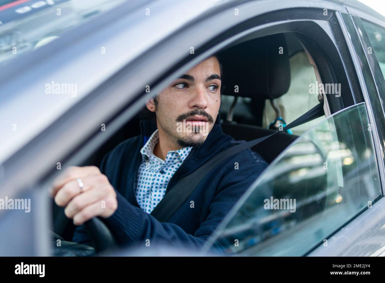 Concentrated young bearded ethnic man with dark hair in smart casual ...