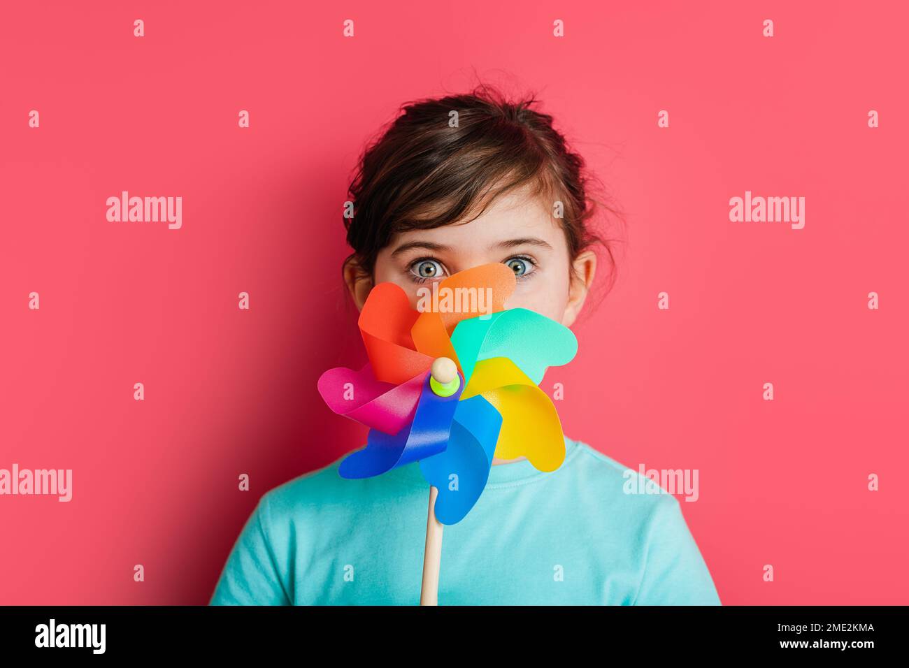 Child in blue t shirt with widely opened eyes covering face with ...