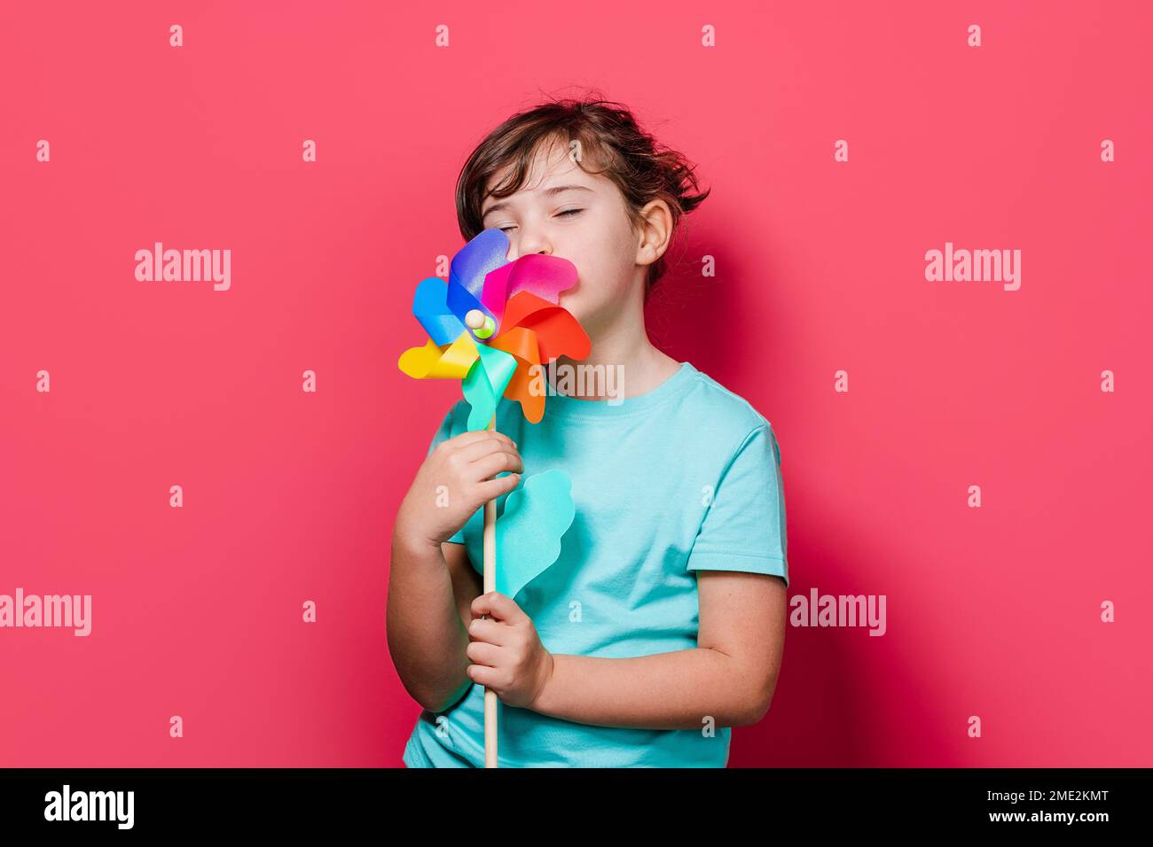 Child in blue t shirt with widely opened eyes covering face with ...