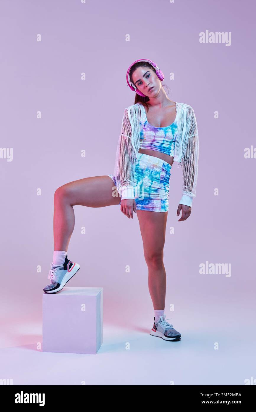 Full body of young sportive female in activewear standing with one leg ...