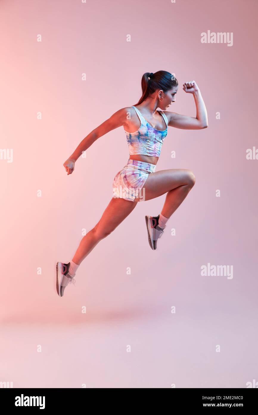Full body side view of fit young female in colorful top and shorts ...