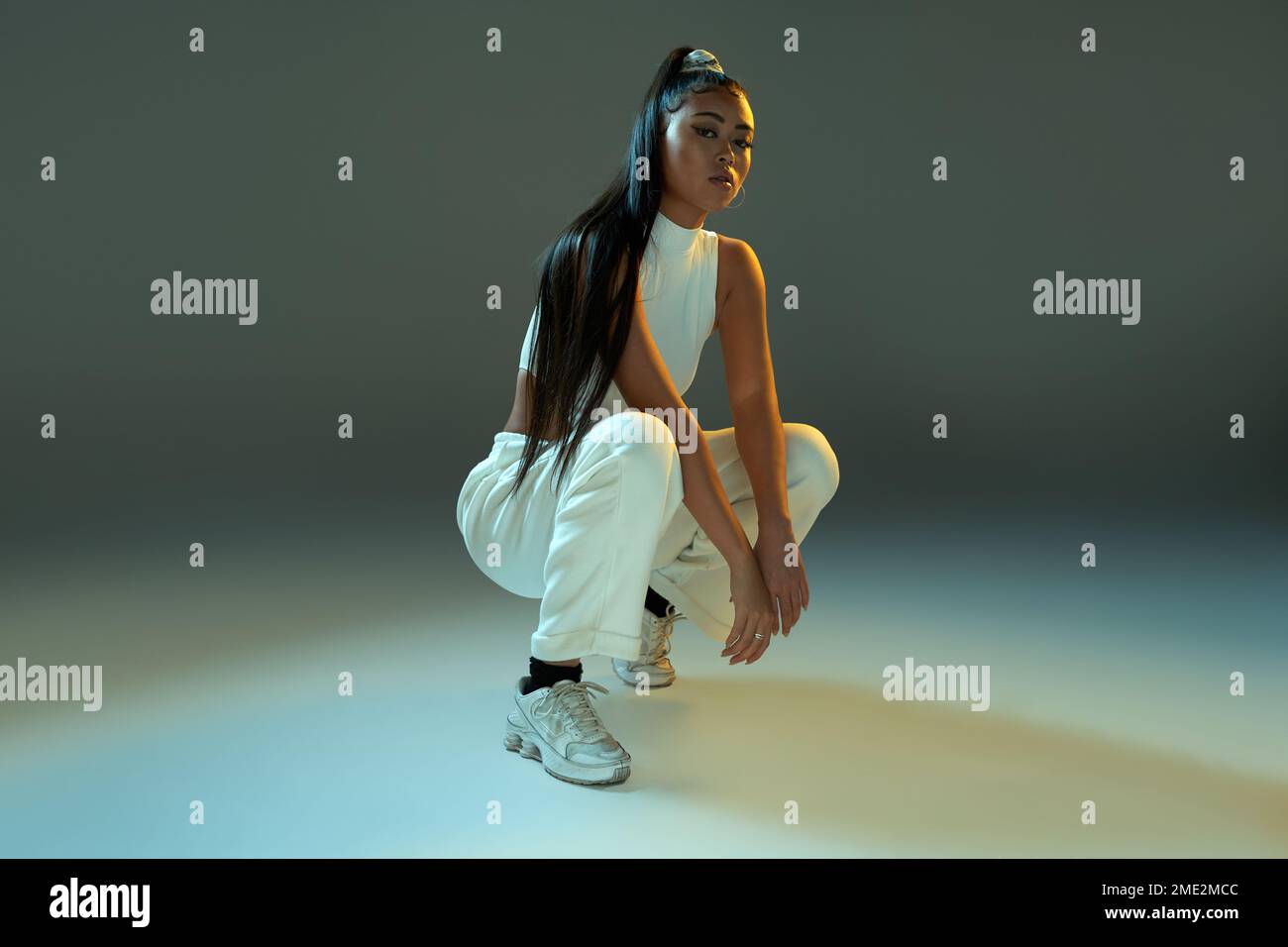 Full body of confident woman in white outfit with long dark ponytail ...