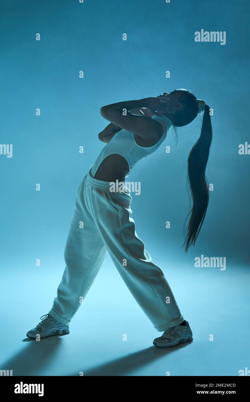 Full body of young female dancer in sportive pants leaning backwards ...