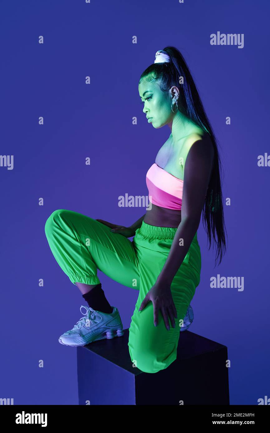 Full body side view of slim female in bra and pants leaning on knee ...