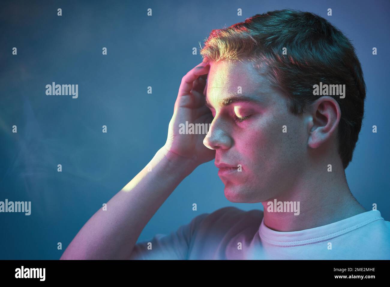 Handsome young male with closed eyes and short haircut standing in neon ...