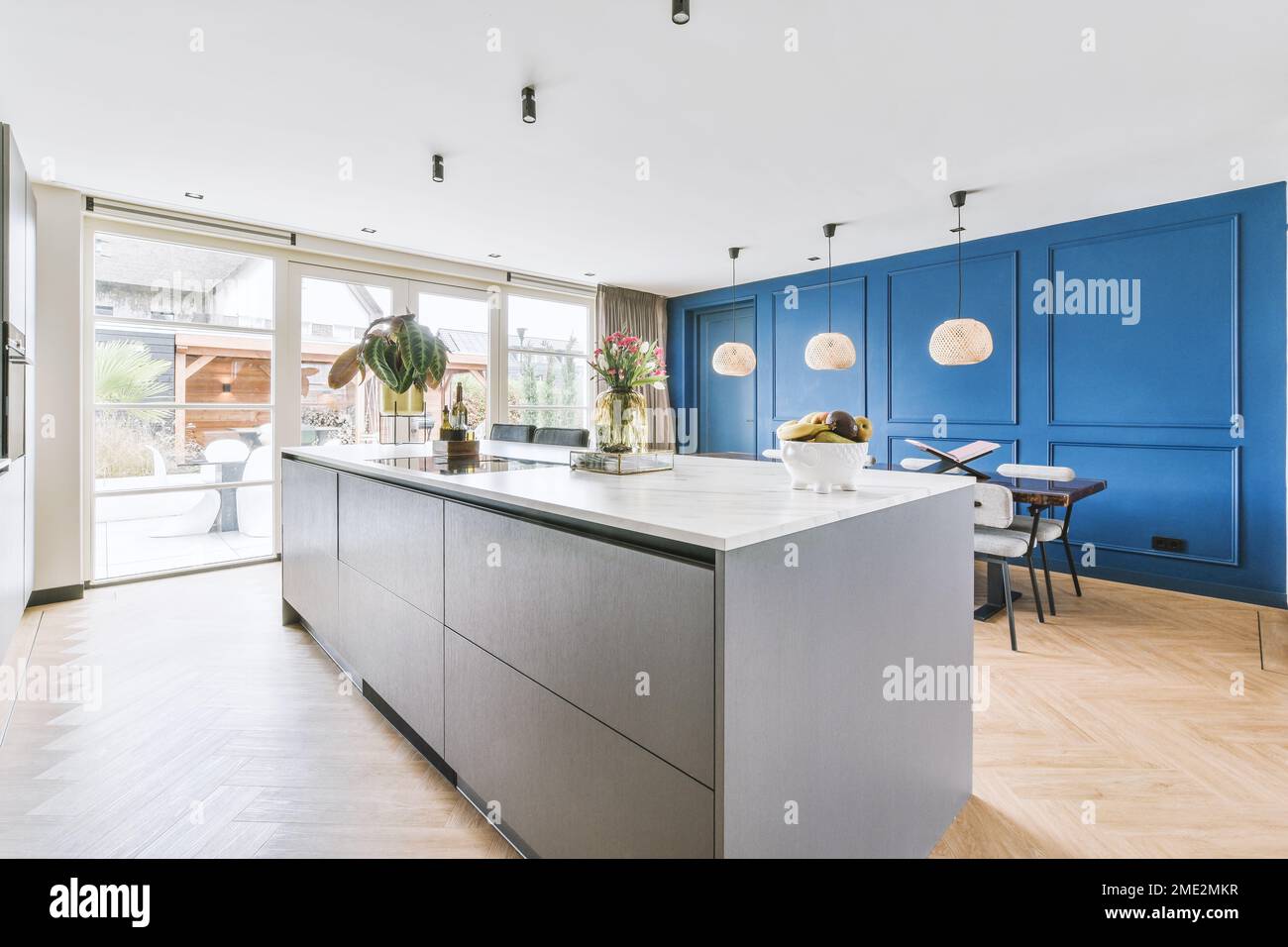 Modern counters with flowers in vase and fruits in bowl located against ...