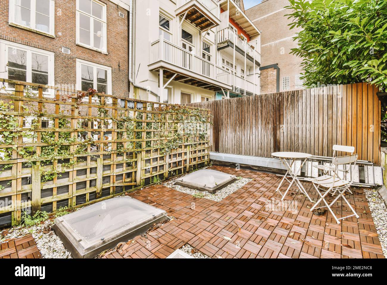 Small fenced terrace with round table chairs and skylights on ground ...