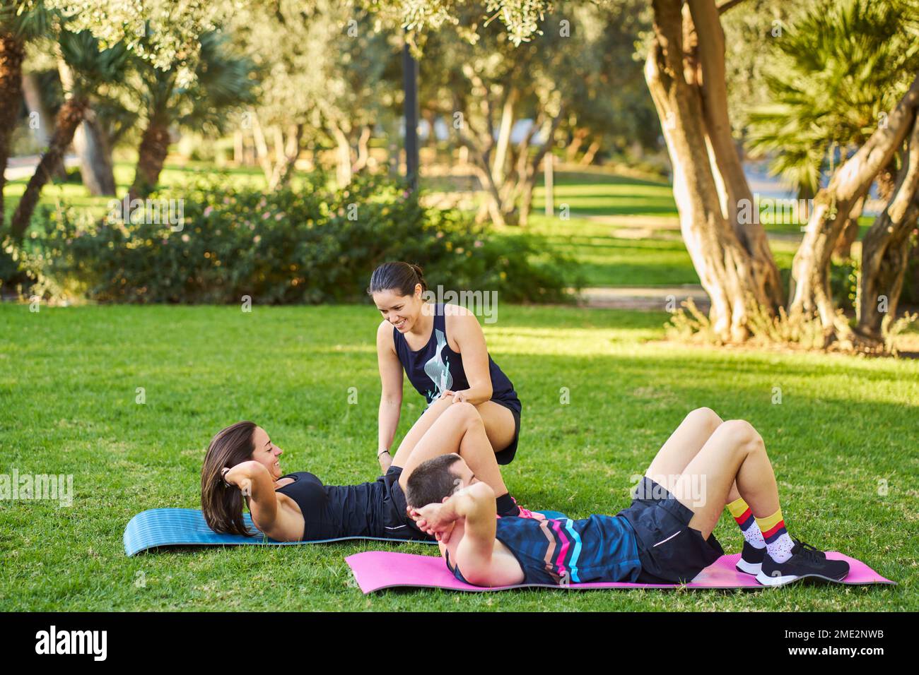 Side view of man and woman lying on mats and doing abs crunch exercise ...
