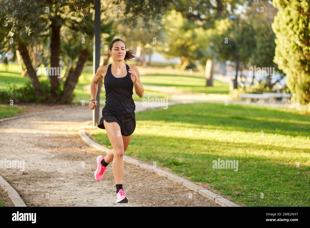 Full body female athlete in activewear running on curvy path during ...