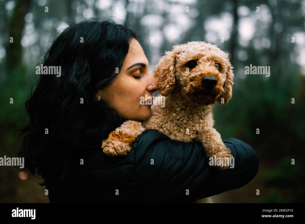 Back view of female owner with adorable puppy on shoulder standing with ...