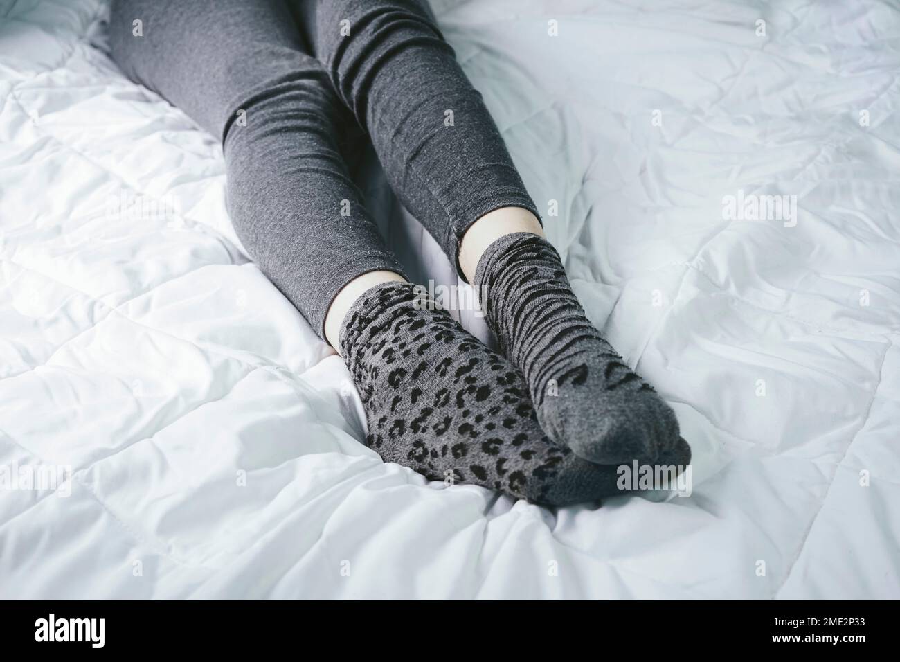 From above of crop anonymous female in grey leggings and socks lying on ...