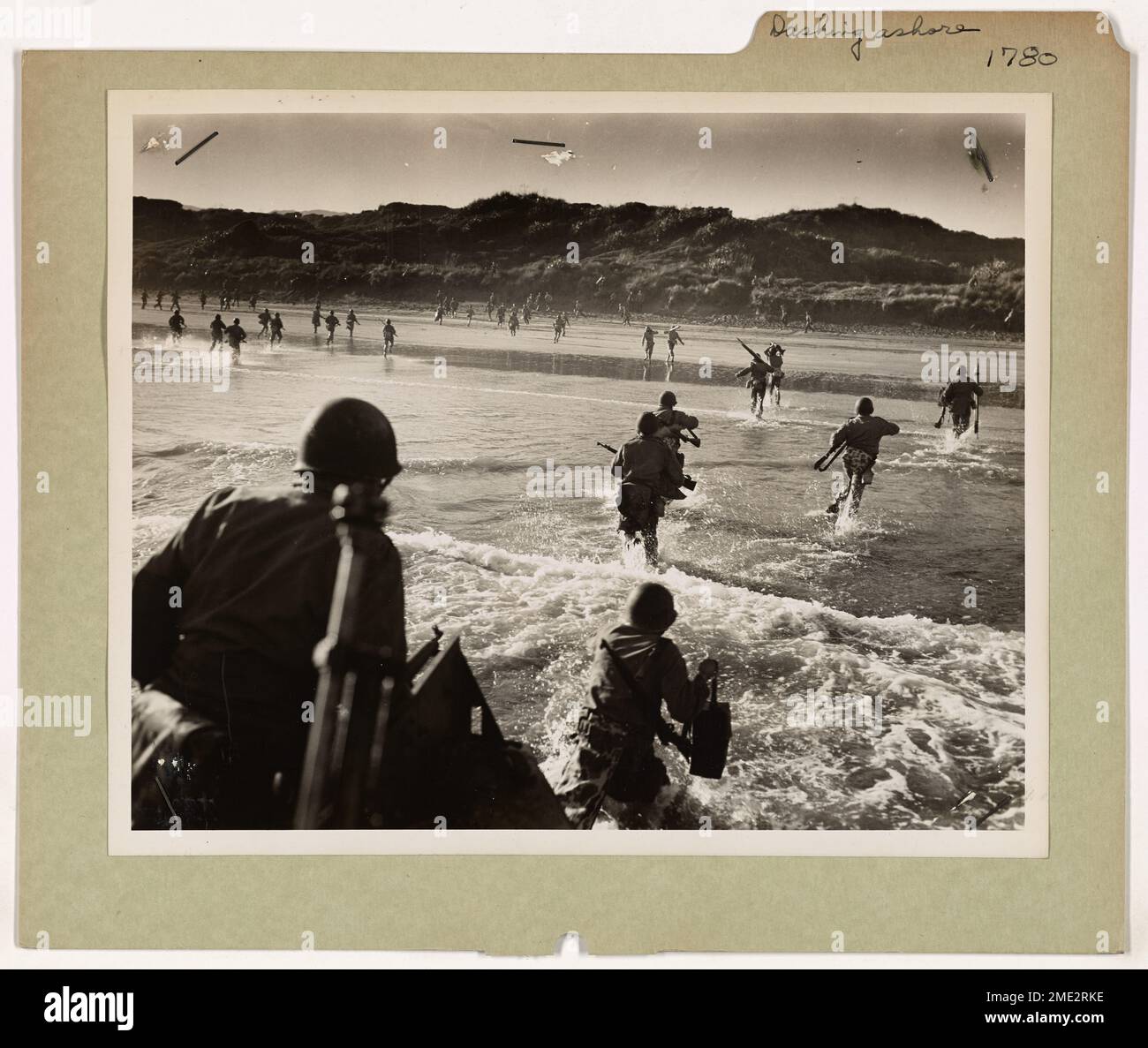 U.S. soldiers run from Coast Guard-manned landing crafts onto the beach ...