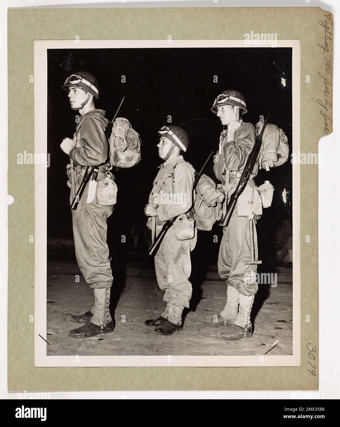 A small Coast Guardsman stands between two taller men, ready to embark ...