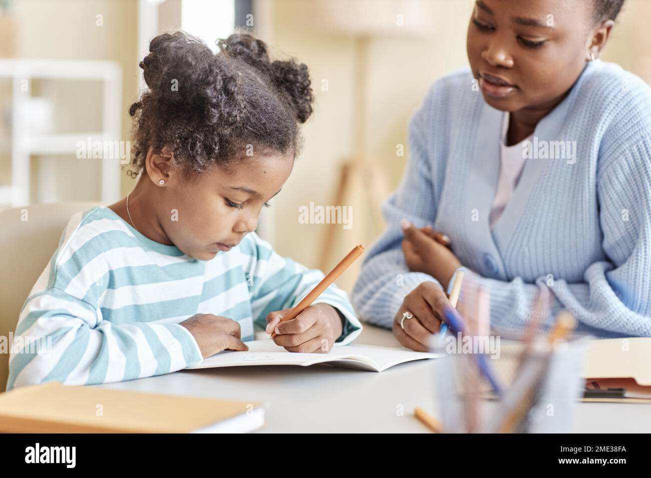 Side view portrait of cute black girl studying with tutor and writing ...