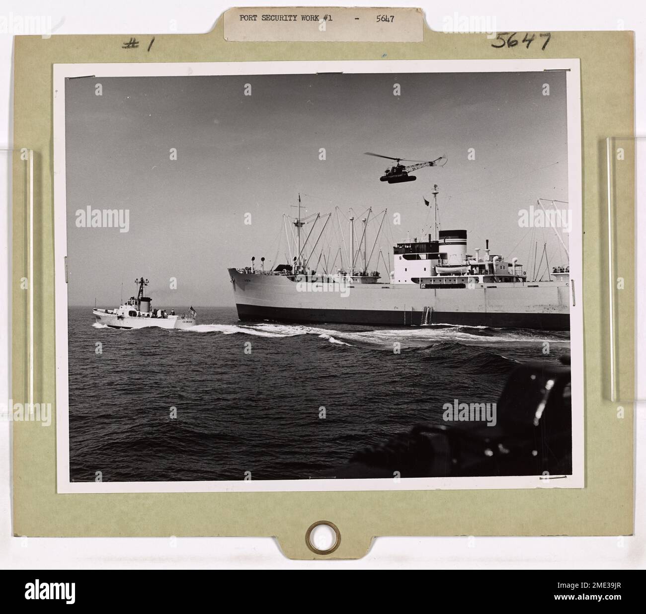 A U.S. Coast Guard vessel and helicopter monitor a foreign vessel in ...