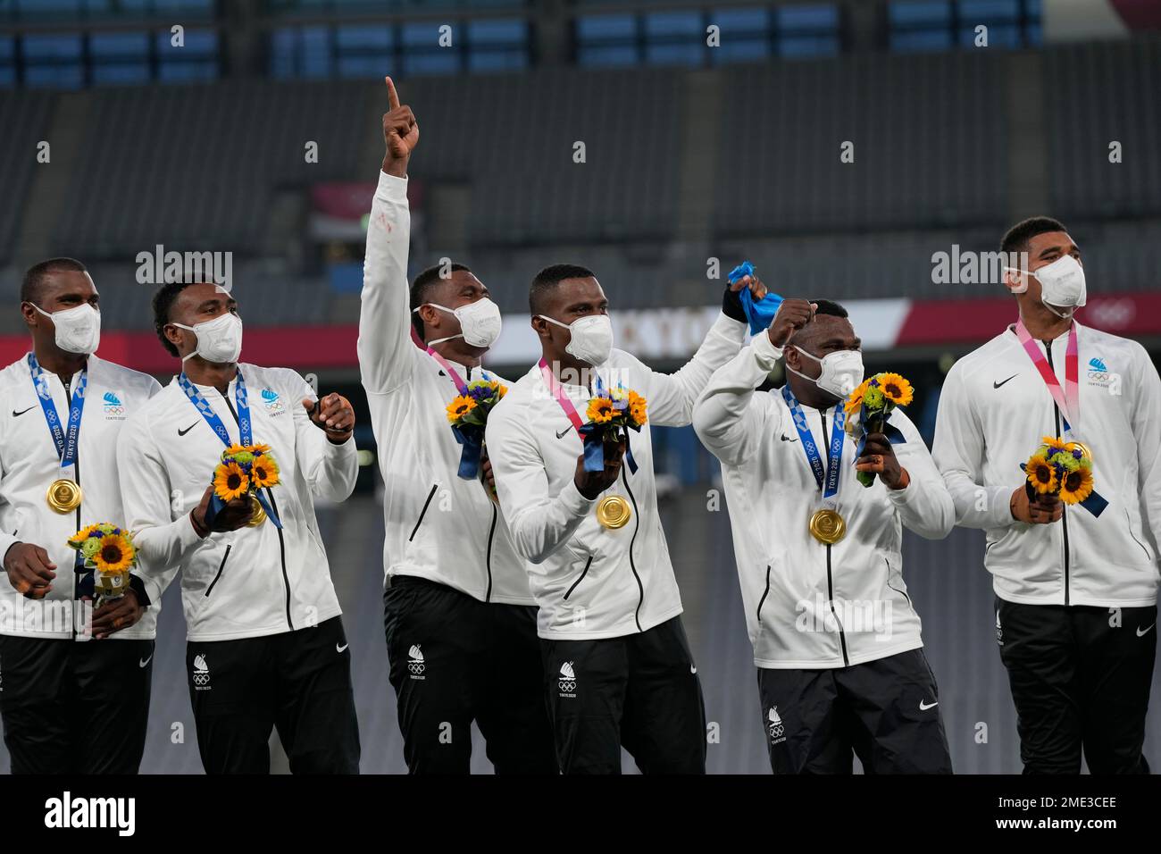Fiji's players wear face masks as they celebrate on the podium with ...