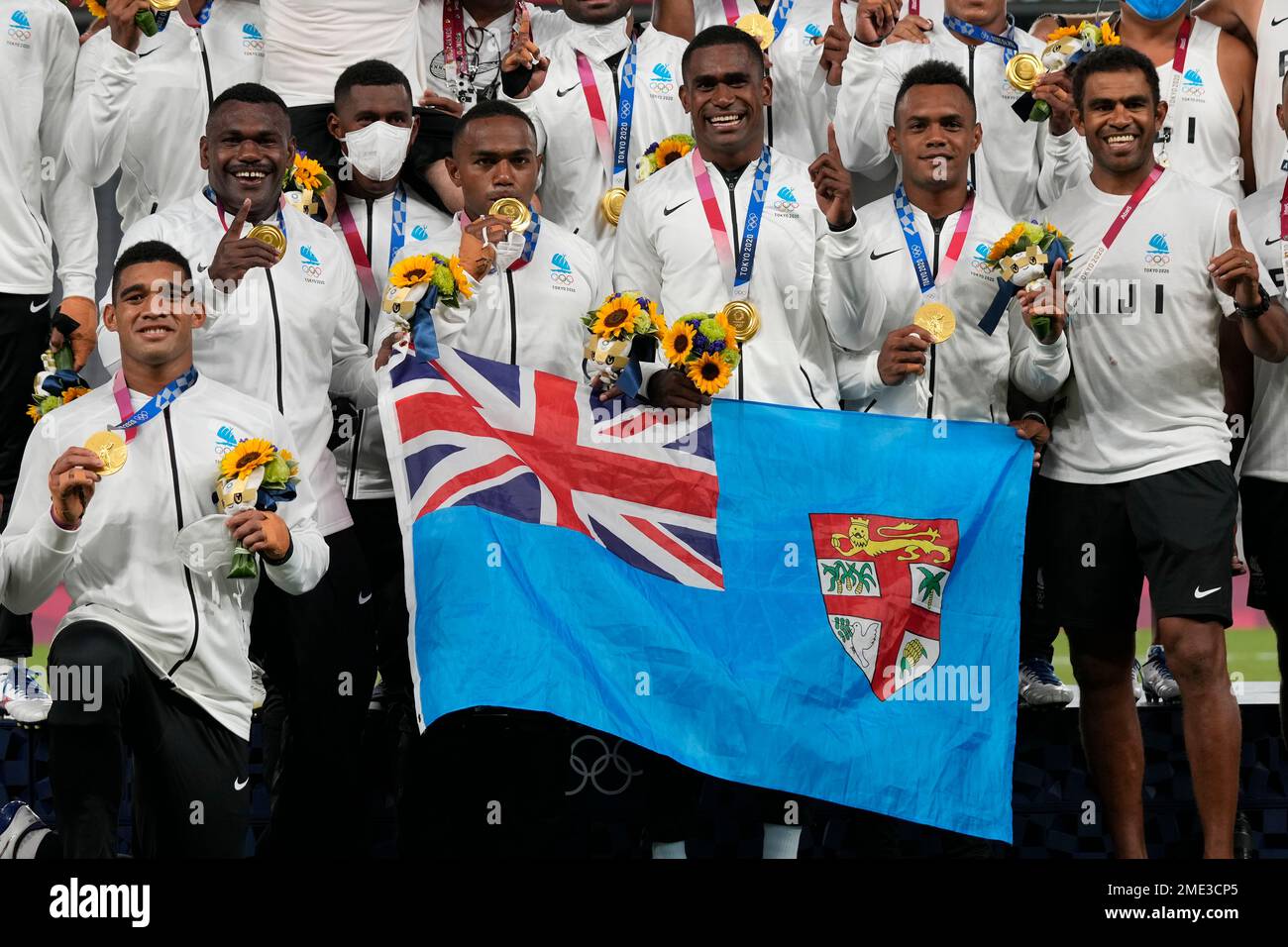 Member's of Fiji's team and staff hold a national flag, as they pose ...