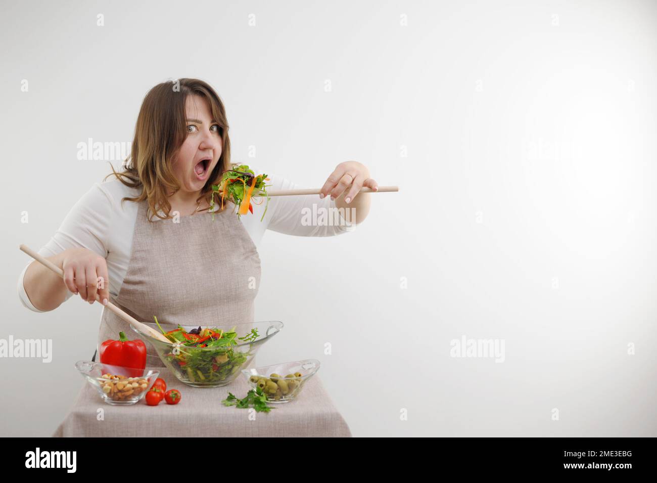 funny cheerful woman eating salad on white background she opens mouth ...