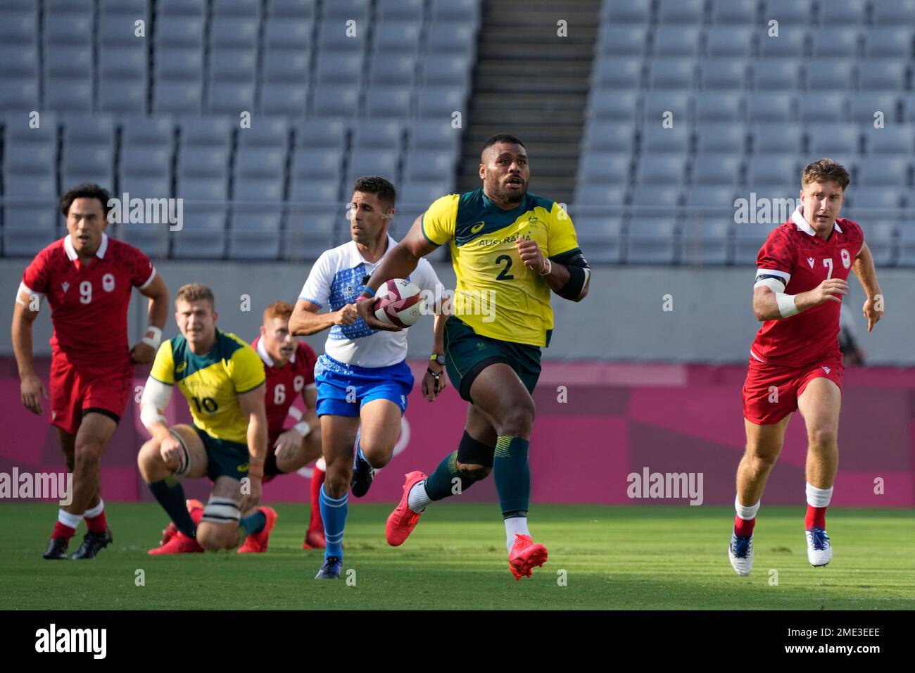 Australia's Samu Kerevi, center, is pursued by Canada's Lucas Hammond ...