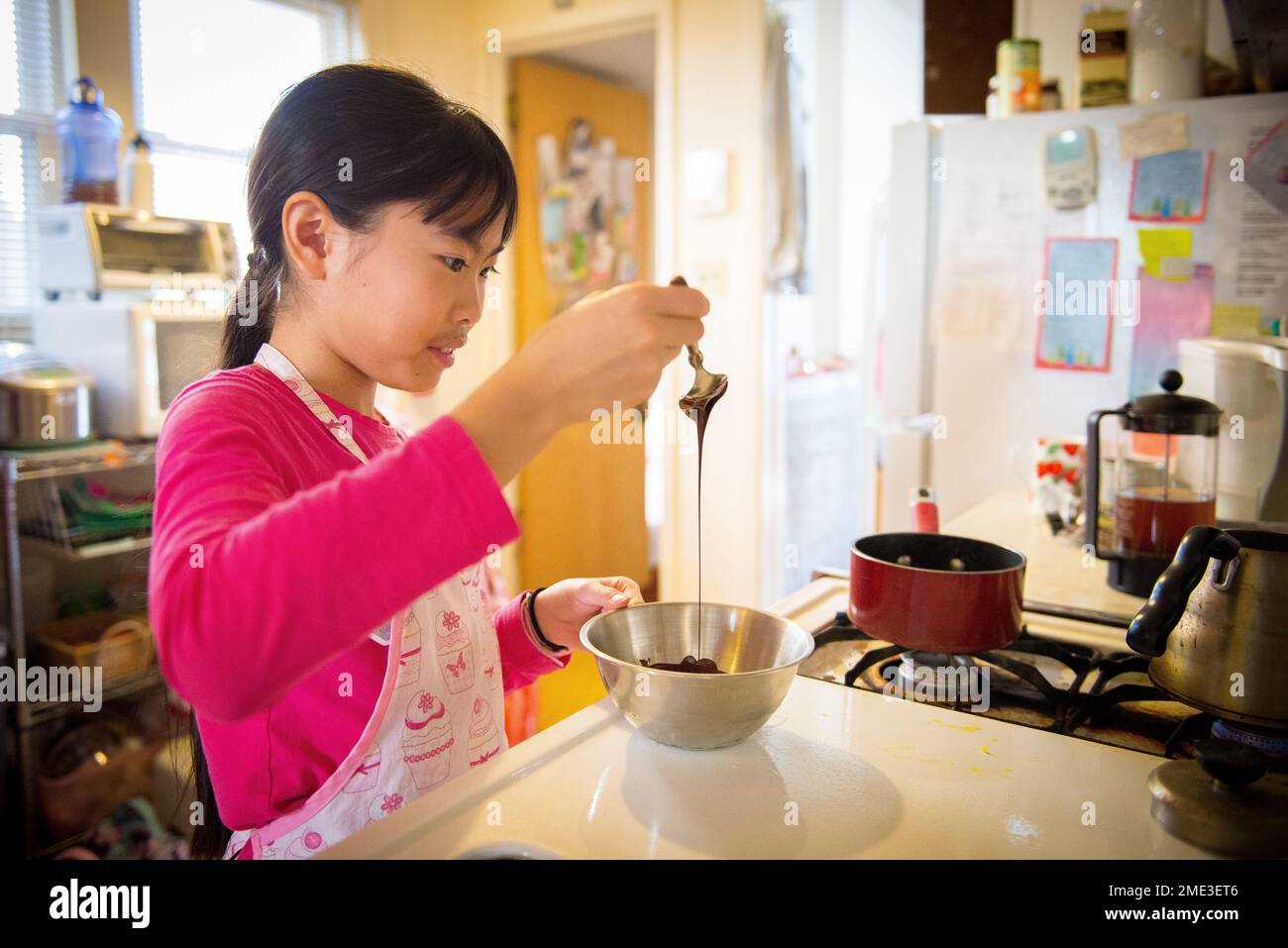 Young asian girl melting chocolate using double boiler for Valentine ...