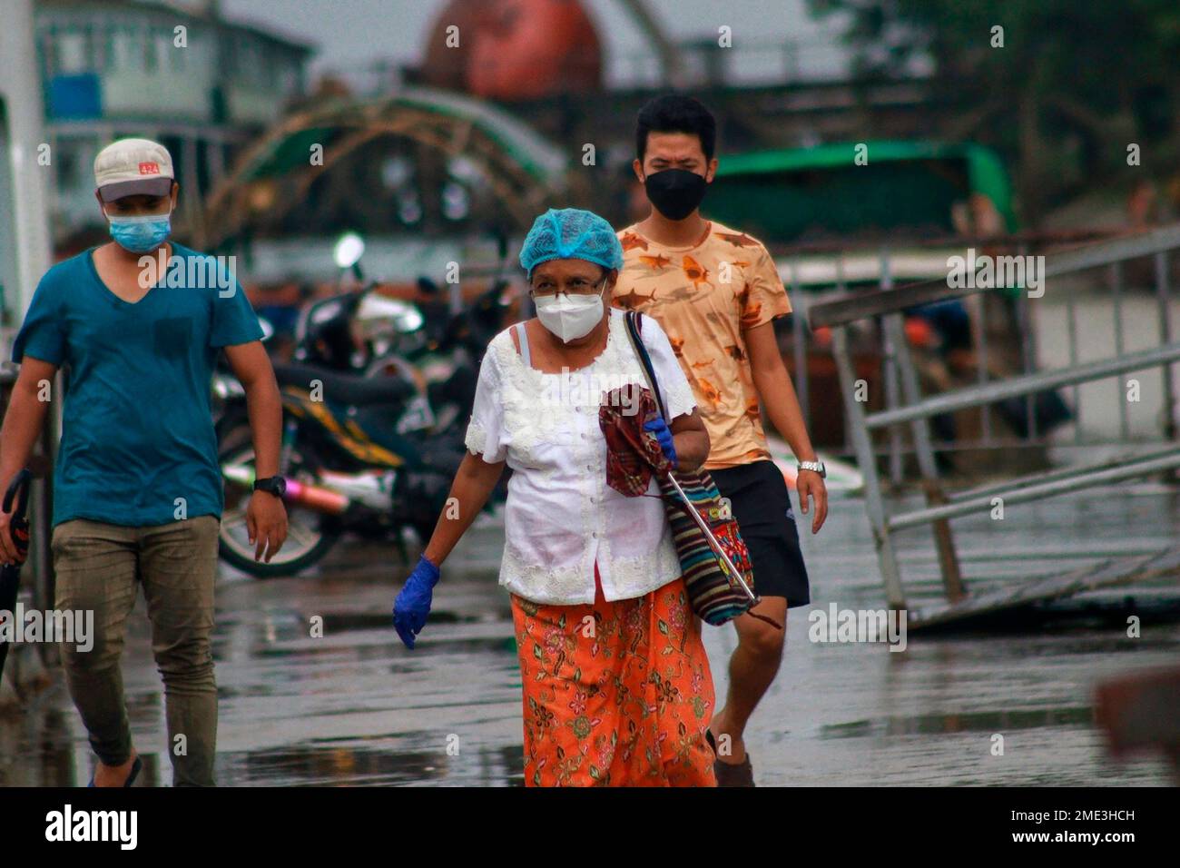 People wear face masks as they walk outside the Dala jetty in Yangon ...