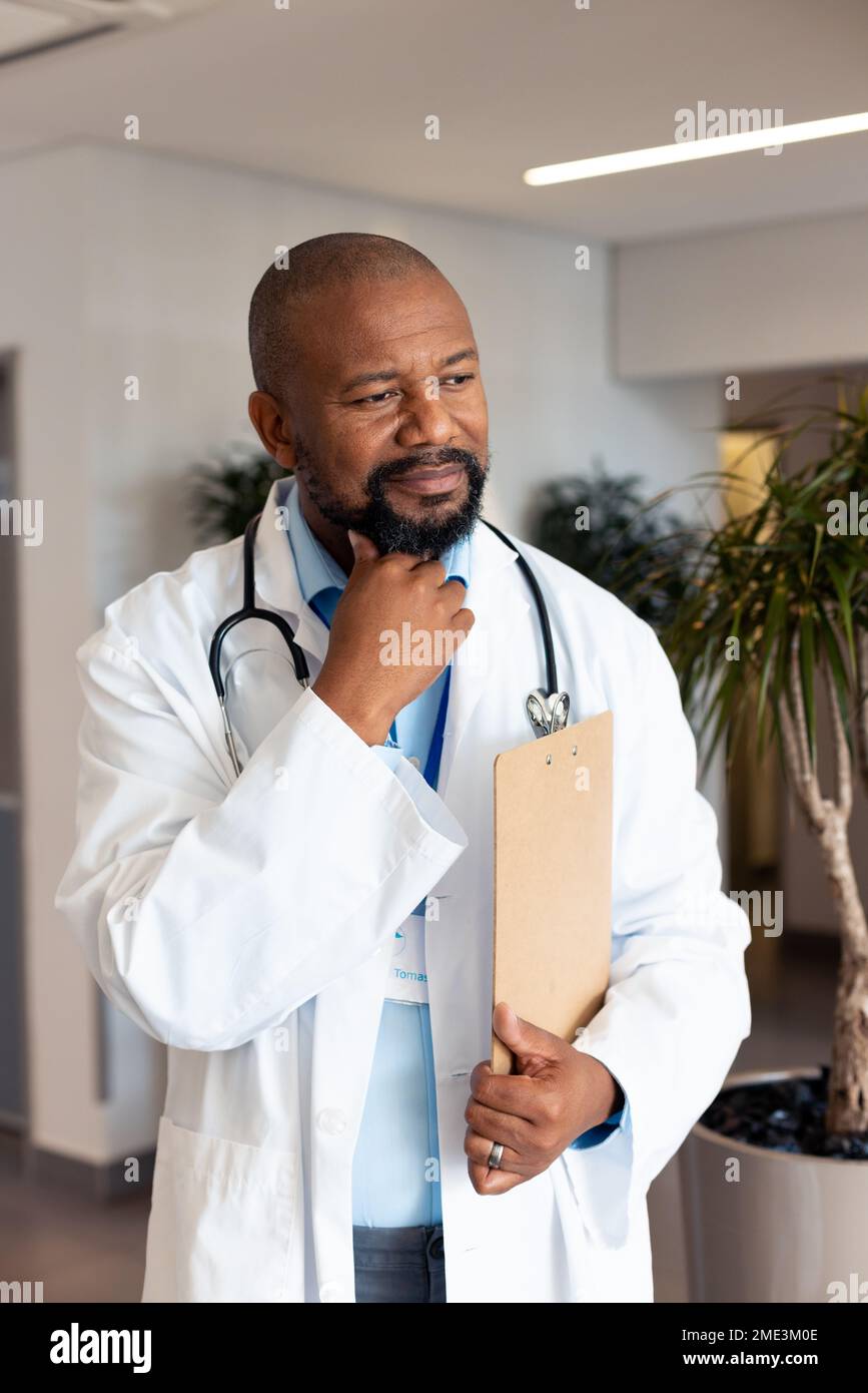 Vertical of thoughtful african american male doctor with clipboard in ...