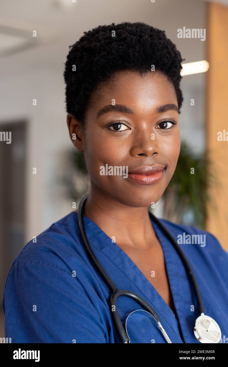 Vertical portrait of smiling african american female doctor in hospital ...