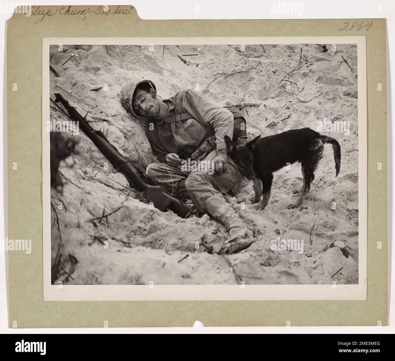 An exhausted American Marine rests in a sandy hollow behind the front ...